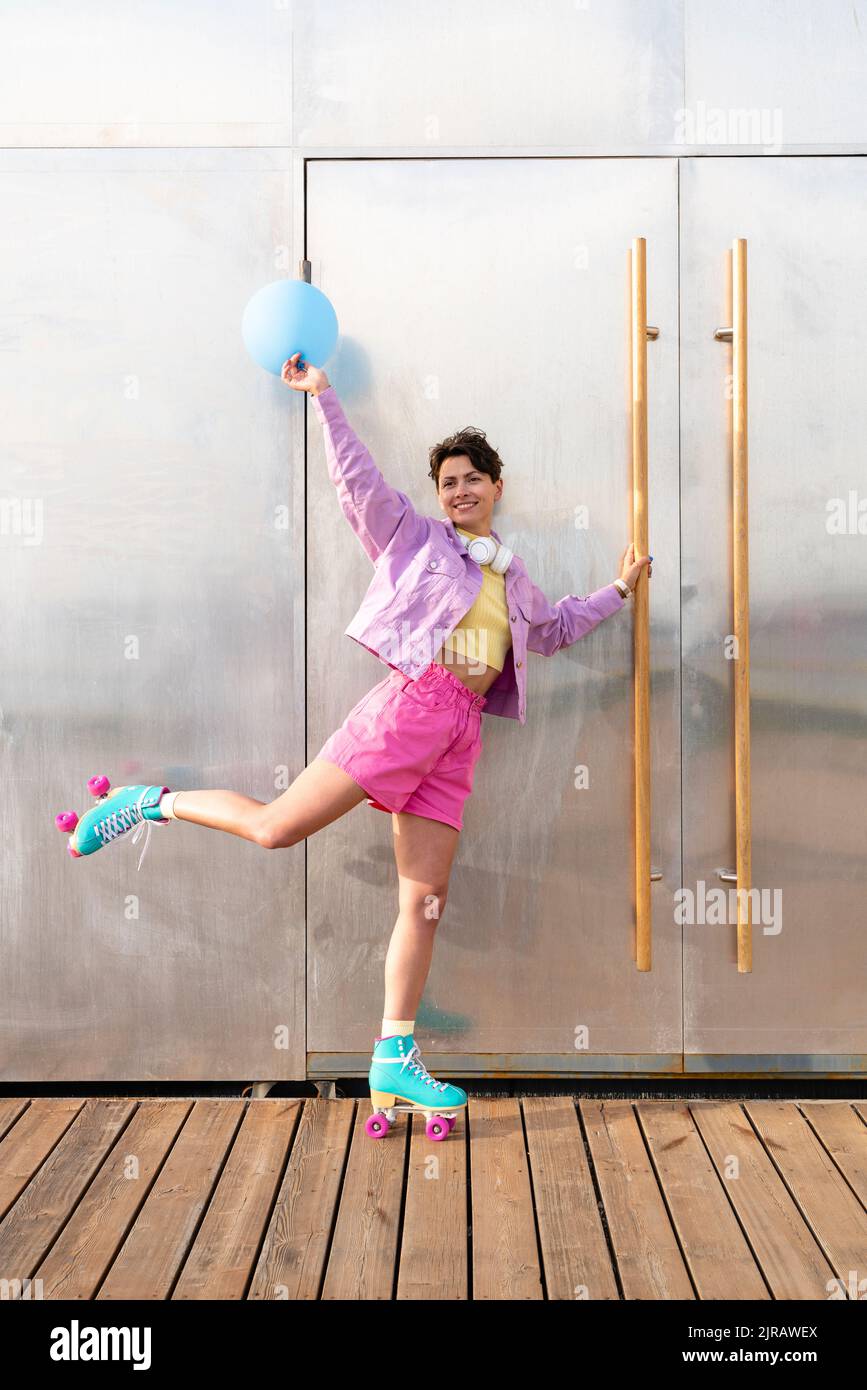 Cheerful woman with blue balloon balancing on roller skates Stock Photo ...