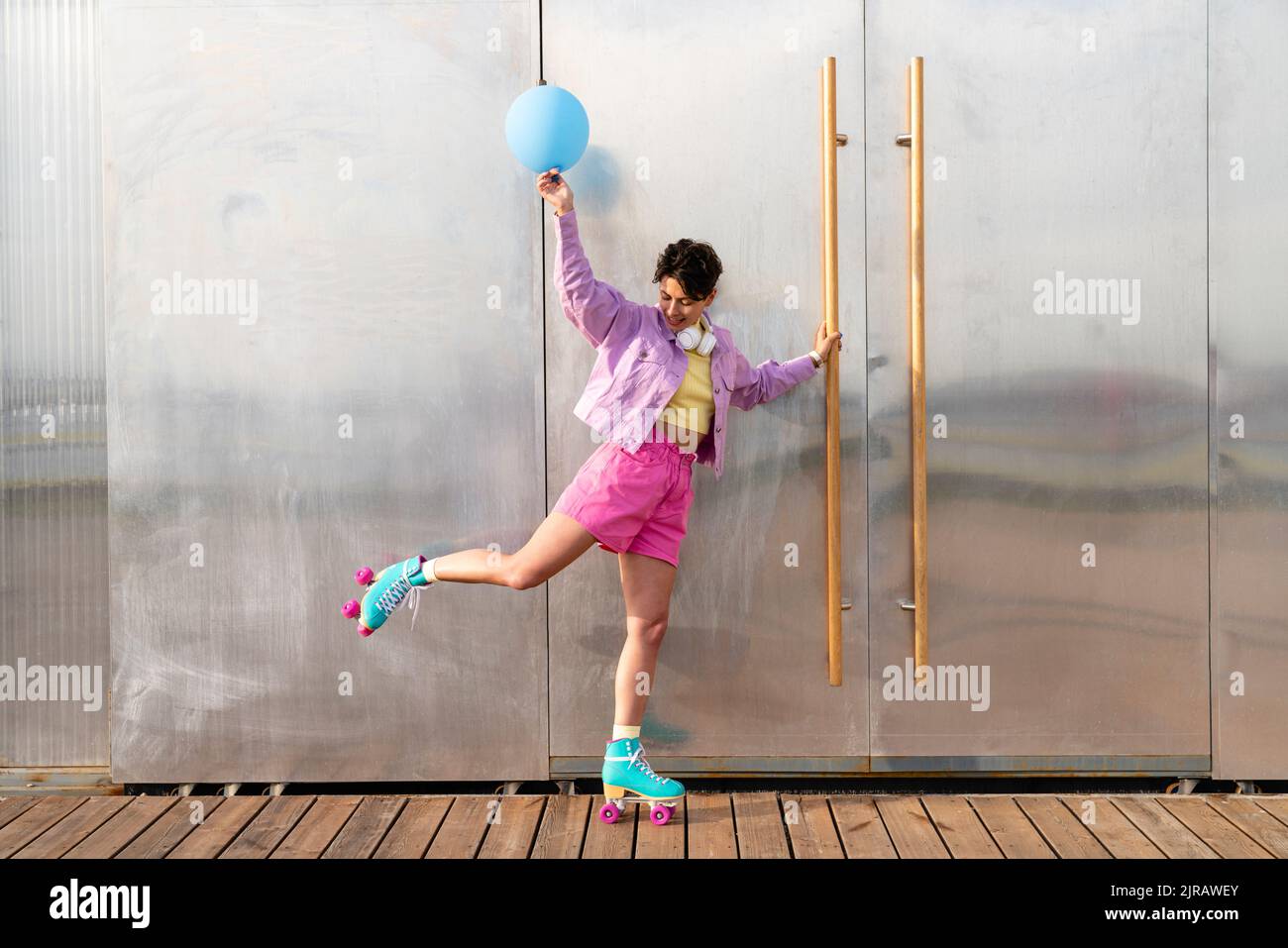 Woman with blue balloon balancing on roller skates by door Stock Photo ...