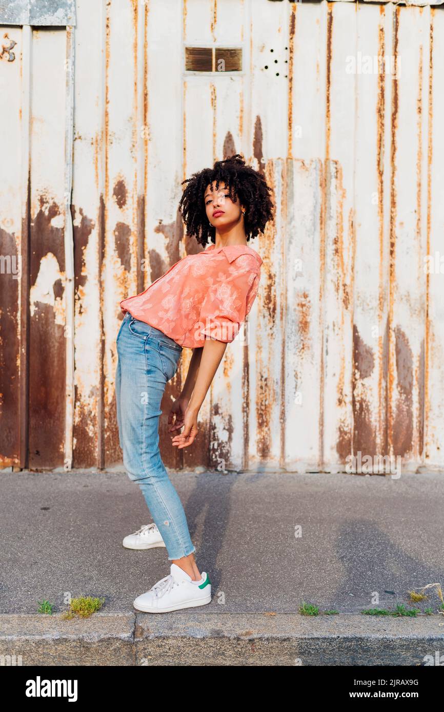 Woman with curly hair bending backwards on footpath Stock Photo - Alamy