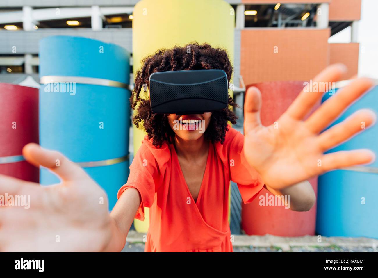 Happy woman wearing virtual reality simulator gesturing in front of ...