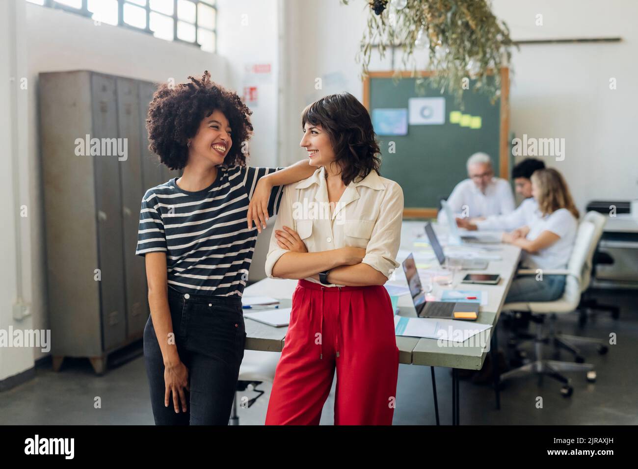 Happy business colleagues looking at each other in office Stock Photo ...