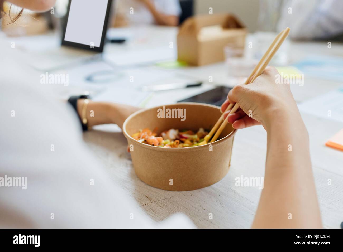Hands of businesswoman with chopsticks having poke bowl in lunch break ...