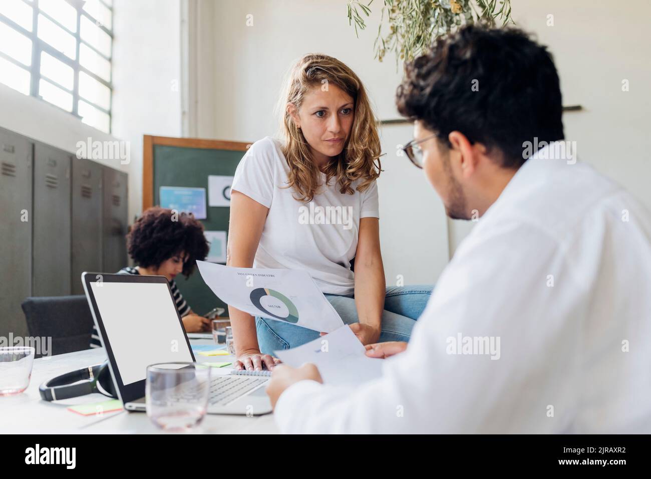 Manager reviewing reports with colleague at work place Stock Photo - Alamy