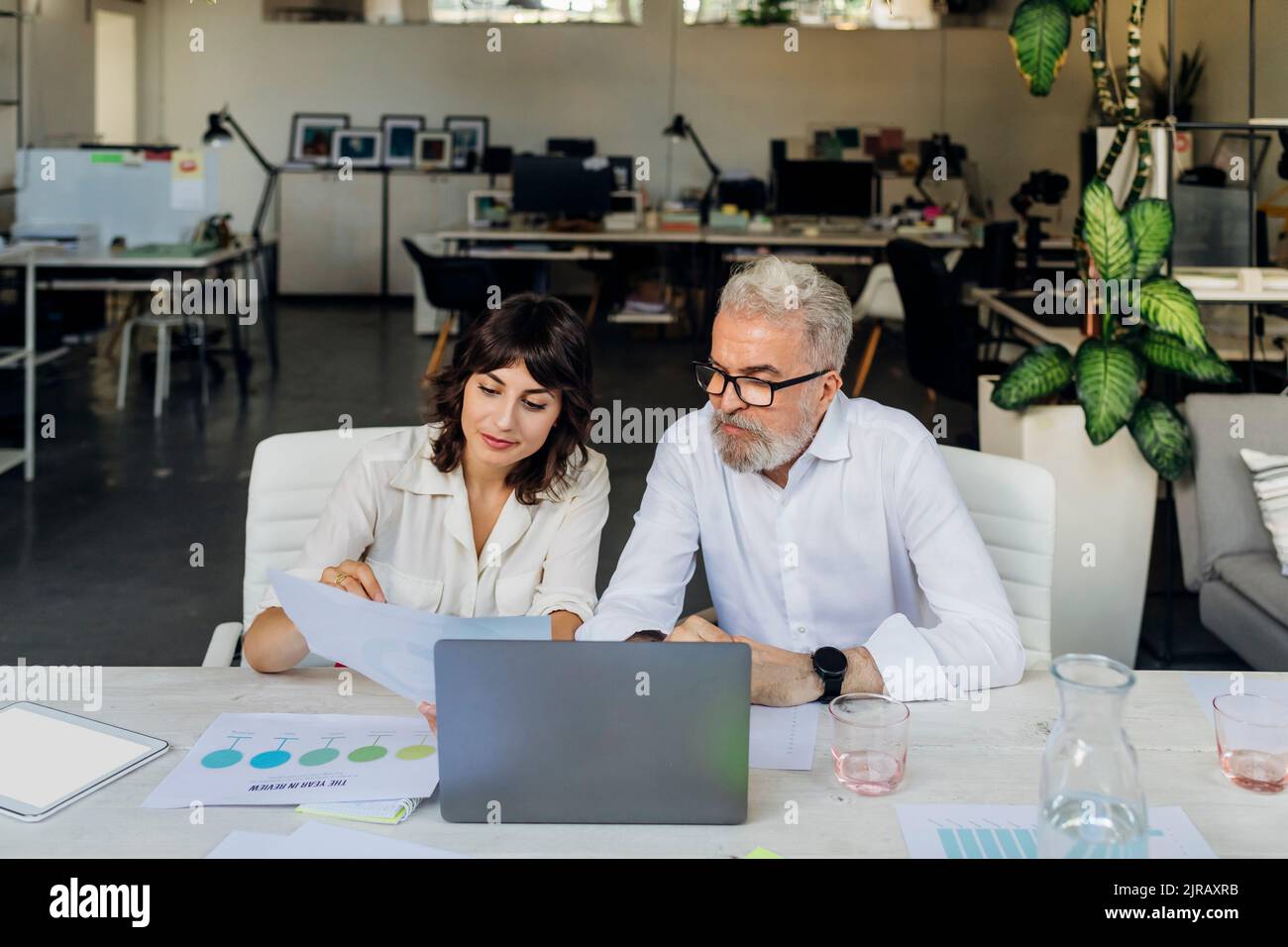 Manager reviewing report with colleague at office Stock Photo - Alamy