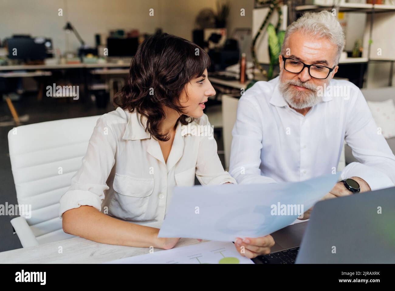 Manager and colleague discussing over report at work place Stock Photo ...