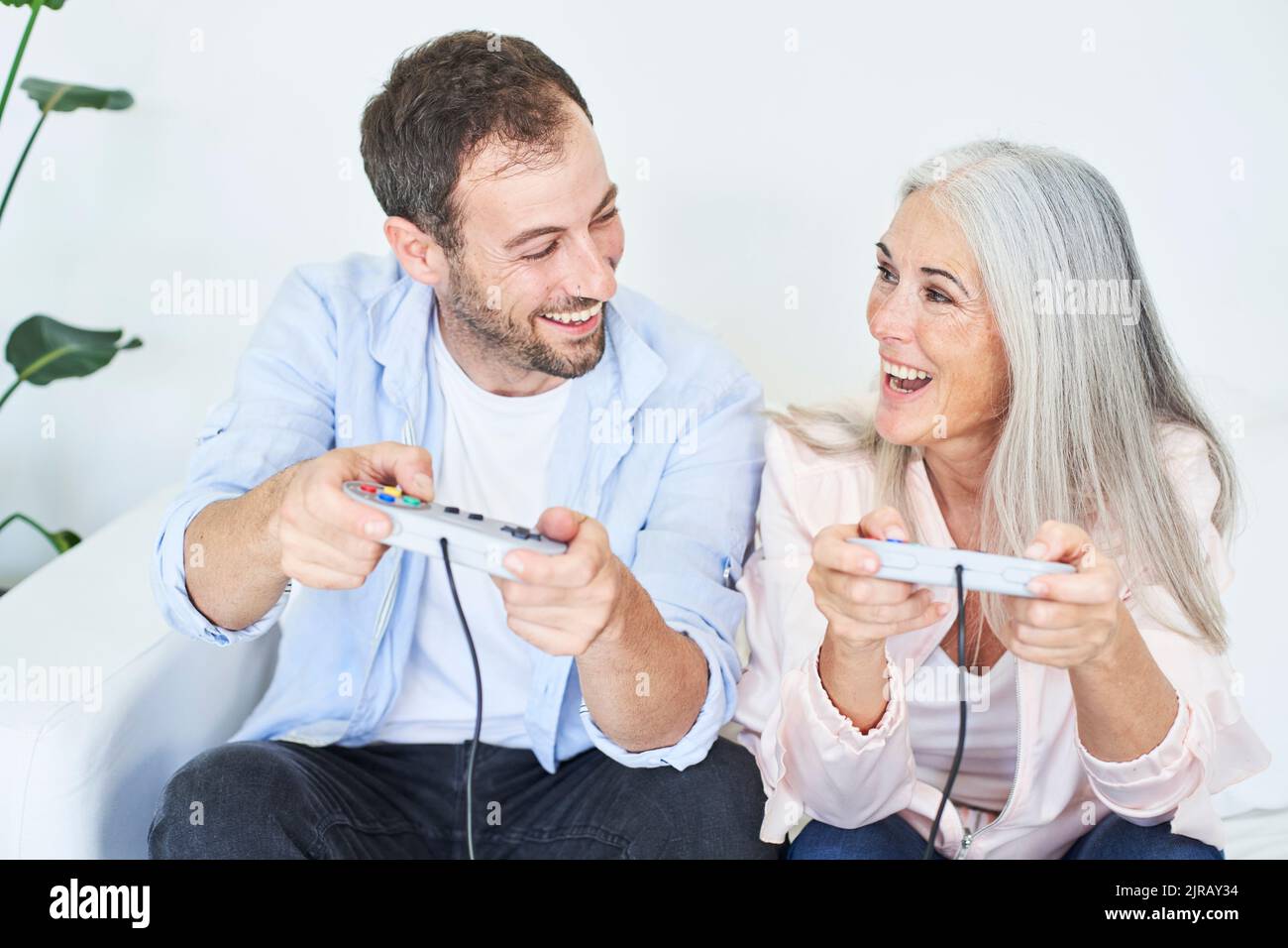 Happy mother and son playing video game with controllers at home Stock ...
