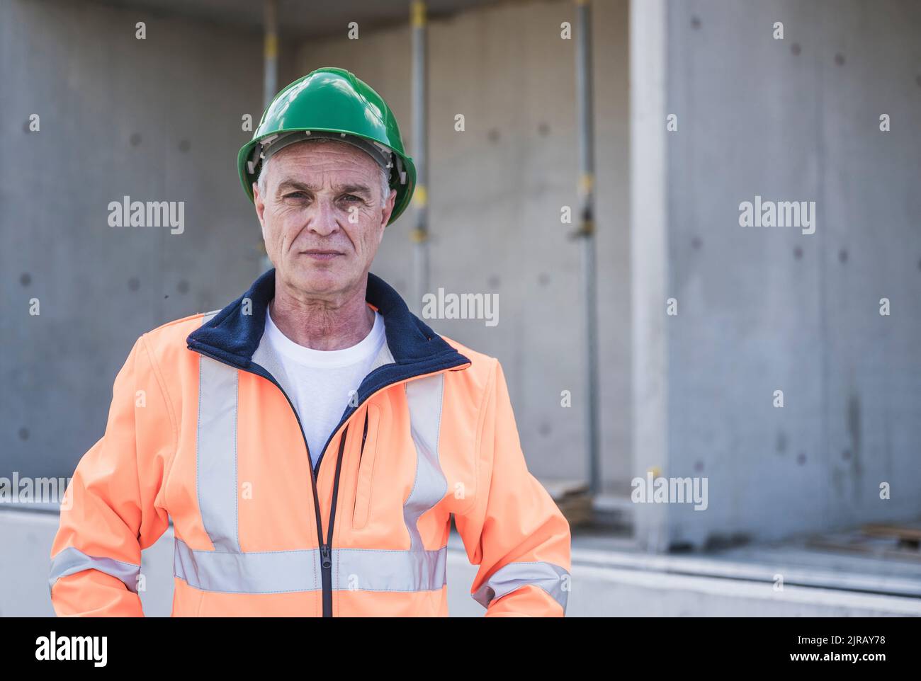 Confident construction worker wearing reflective clothing and hardhat ...