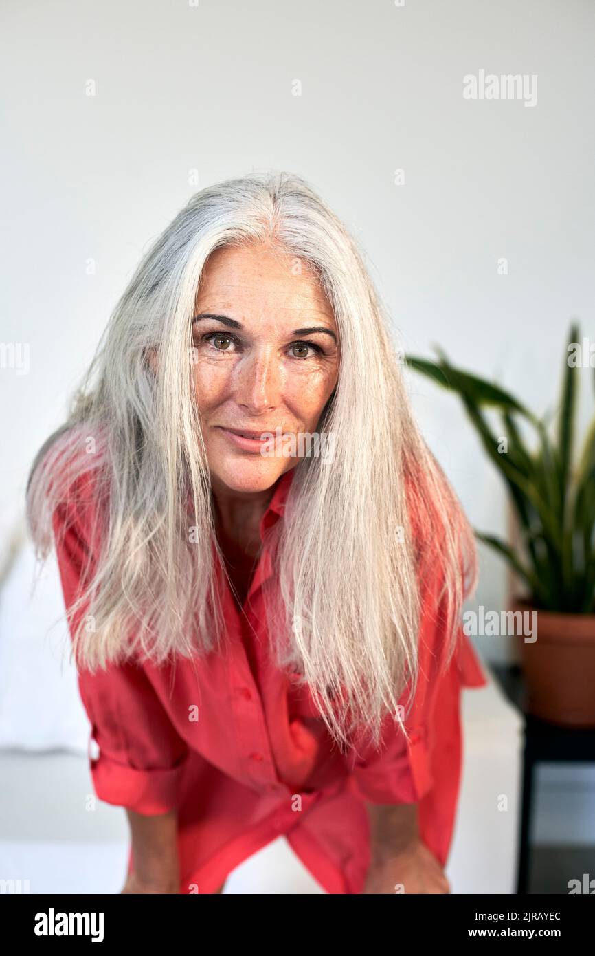 Smiling mature woman with gray hair bending in front of wall Stock ...