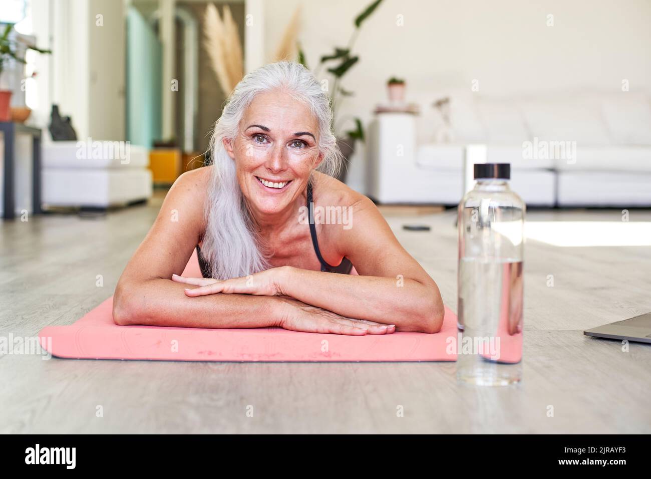 Happy woman lying on exercise mat at home Stock Photo - Alamy