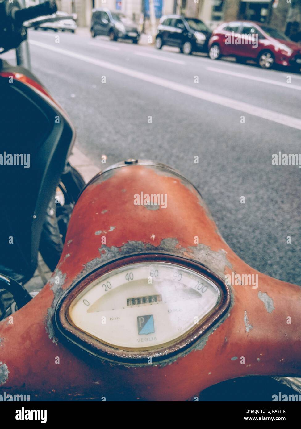 A vertical closeup shot of the sppedometer of red Italian Vespa scooter ...