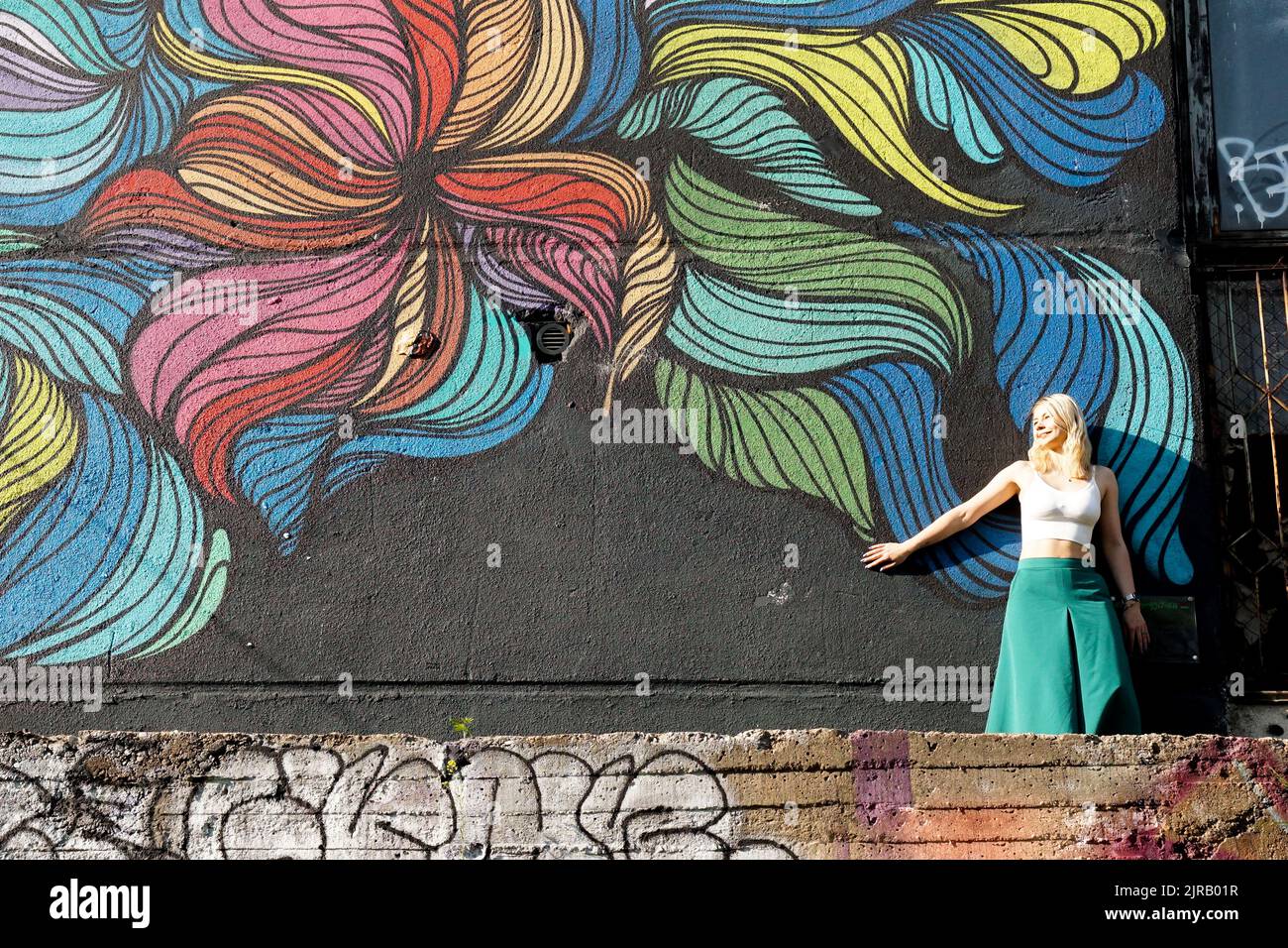Portrait of a smiling woman in the rays of the sun on a graffiti ...