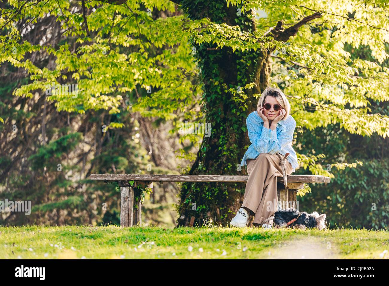 Mature woman wearing sunglasses sitting with head in hands on bench at ...
