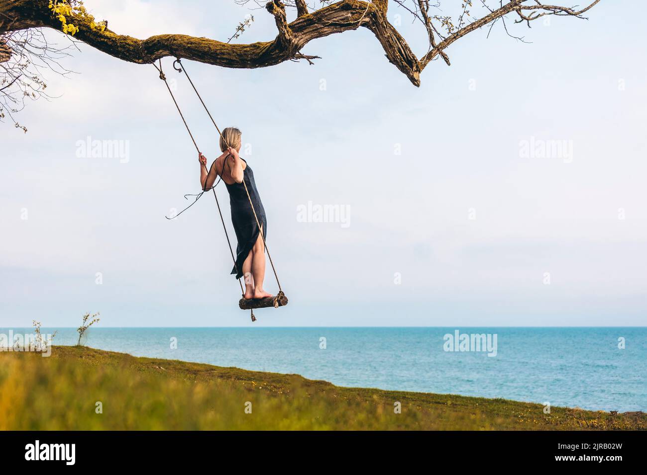 Mature woman balancing on swing in front of sky Stock Photo - Alamy
