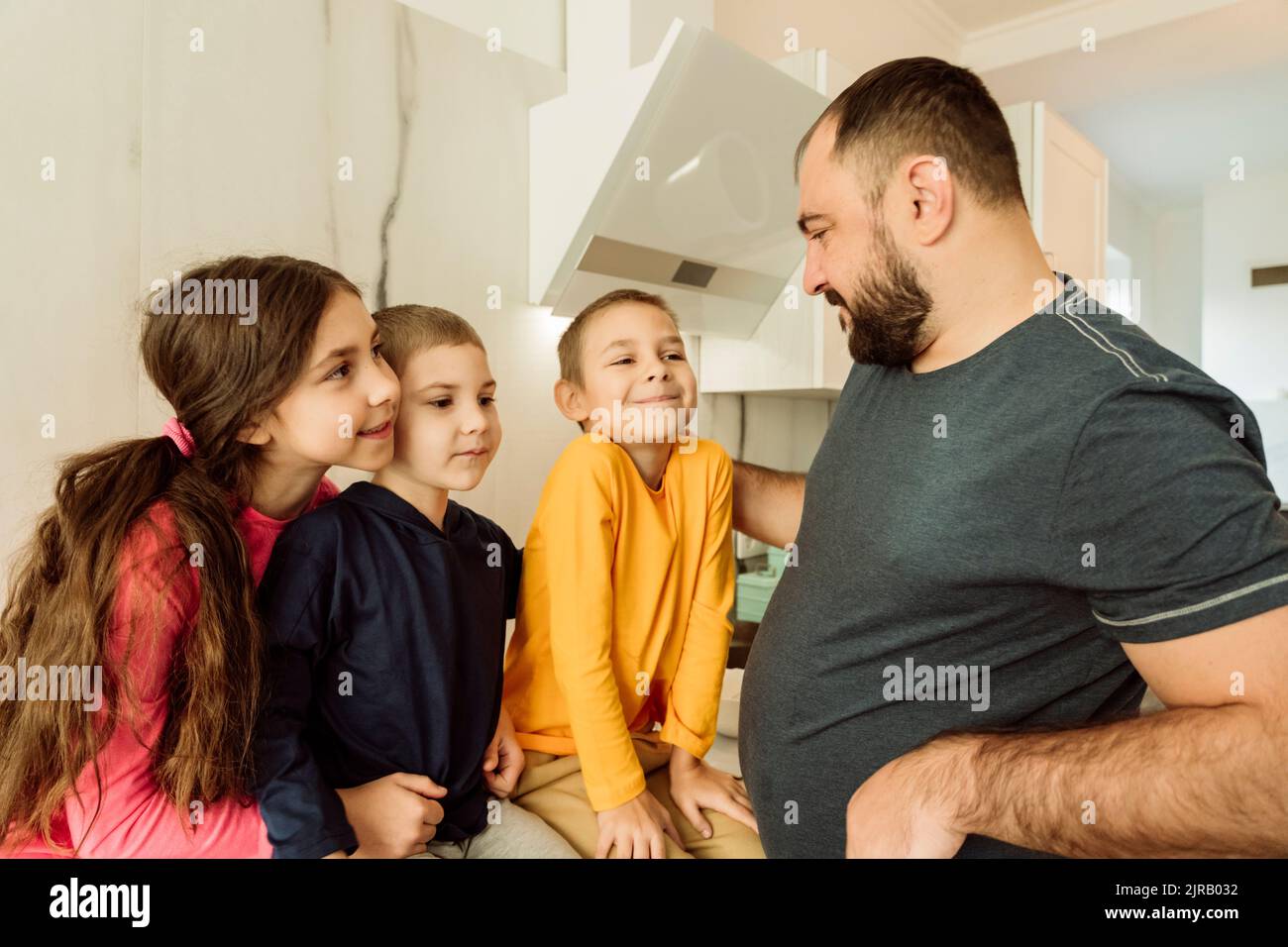 Smiling father talking with children in kitchen Stock Photo - Alamy