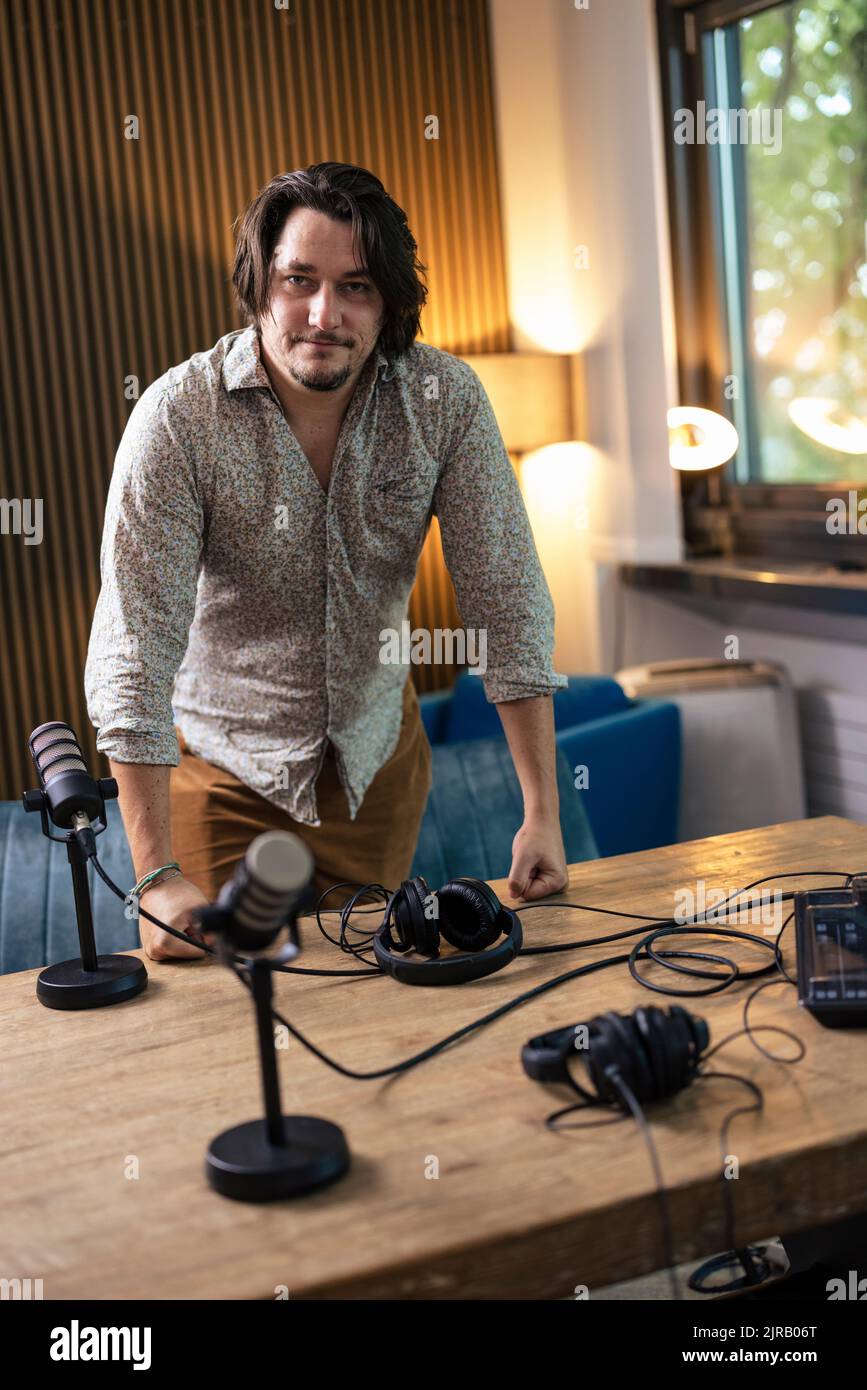 Presenter leaning on desk with microphone in recording studio Stock ...