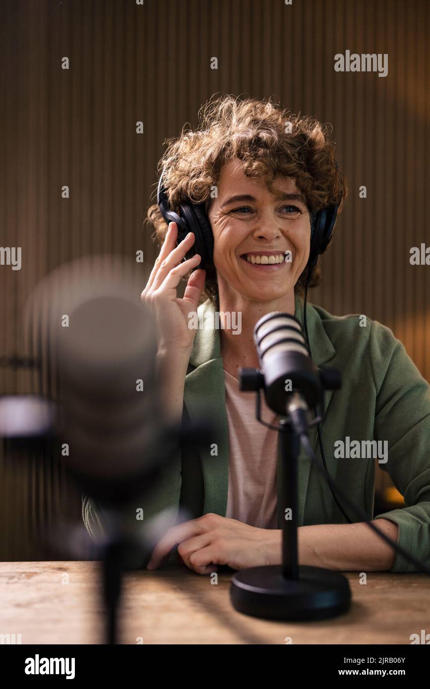 Happy presenter wearing headset sitting in recording studio Stock Photo ...