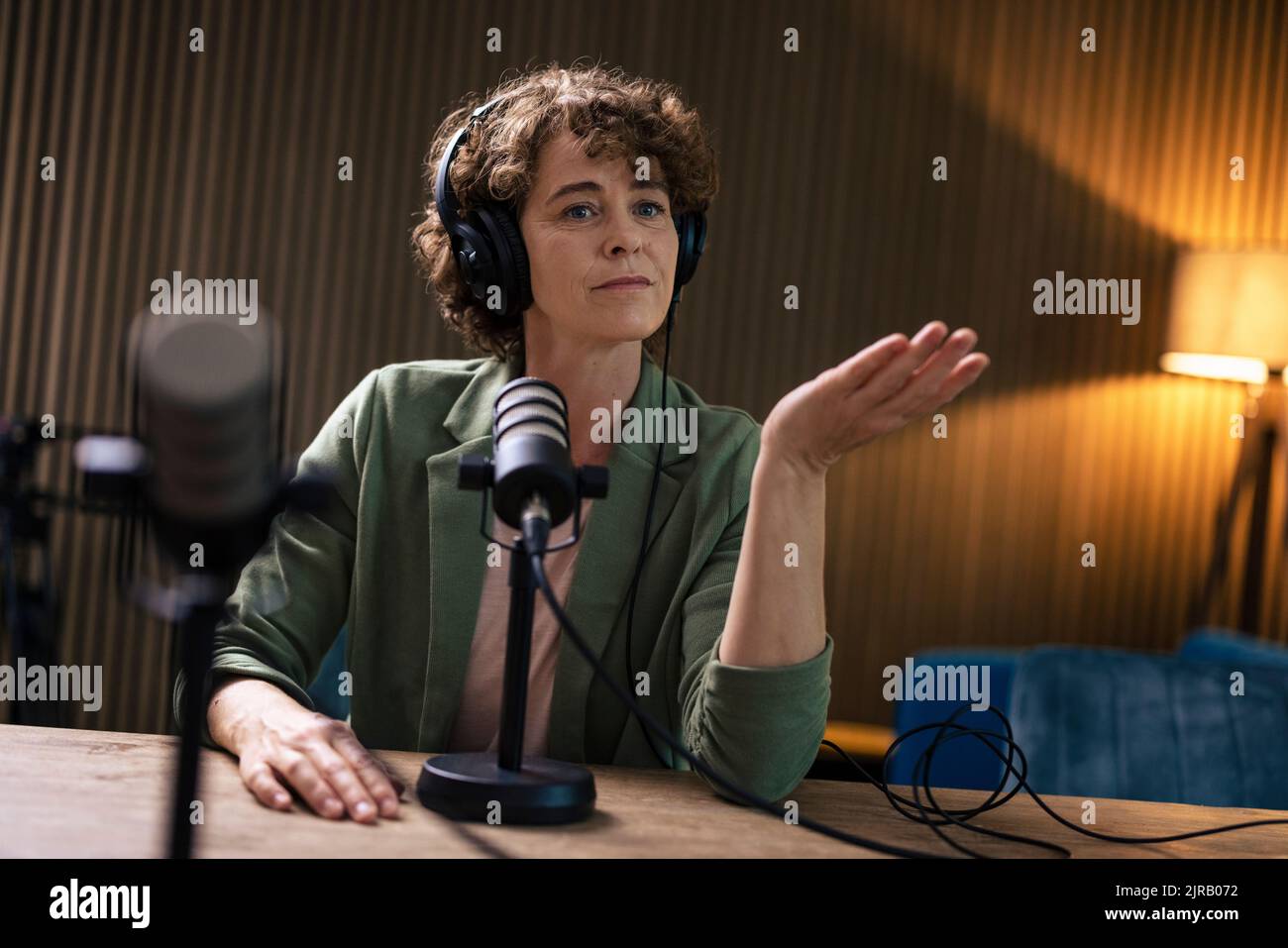 Presenter wearing headset gesturing sitting with microphone at radio ...