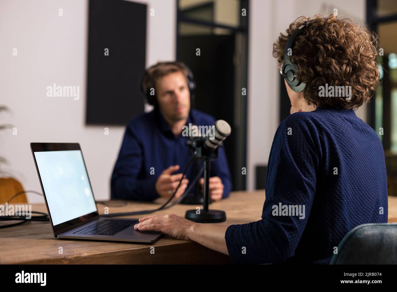 Presenter wearing headset interviewing guest in recording studio Stock ...