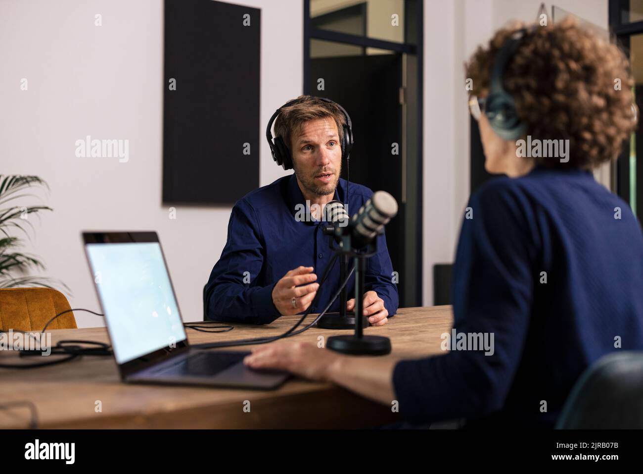Man wearing headset talking with guest in recording studio Stock Photo ...