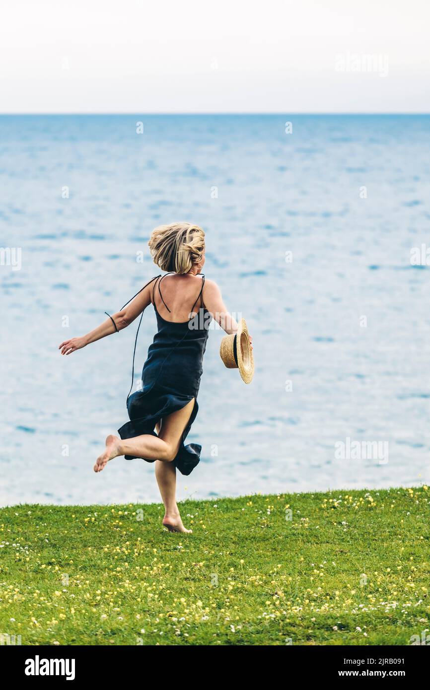 Mature woman with arms outstretched running in front of sea Stock Photo ...