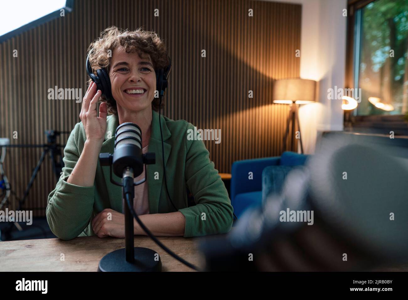 Happy presenter wearing headset recording podcast in radio station ...