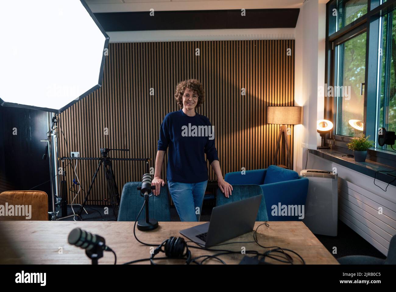 Smiling presenter standing amidst chair at radio station Stock Photo ...