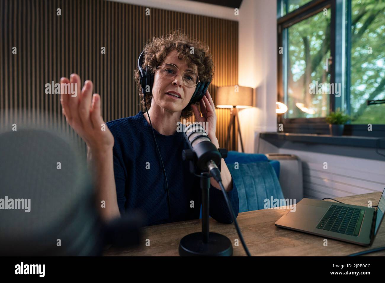 Presenter wearing headset recording through microphone at radio station ...