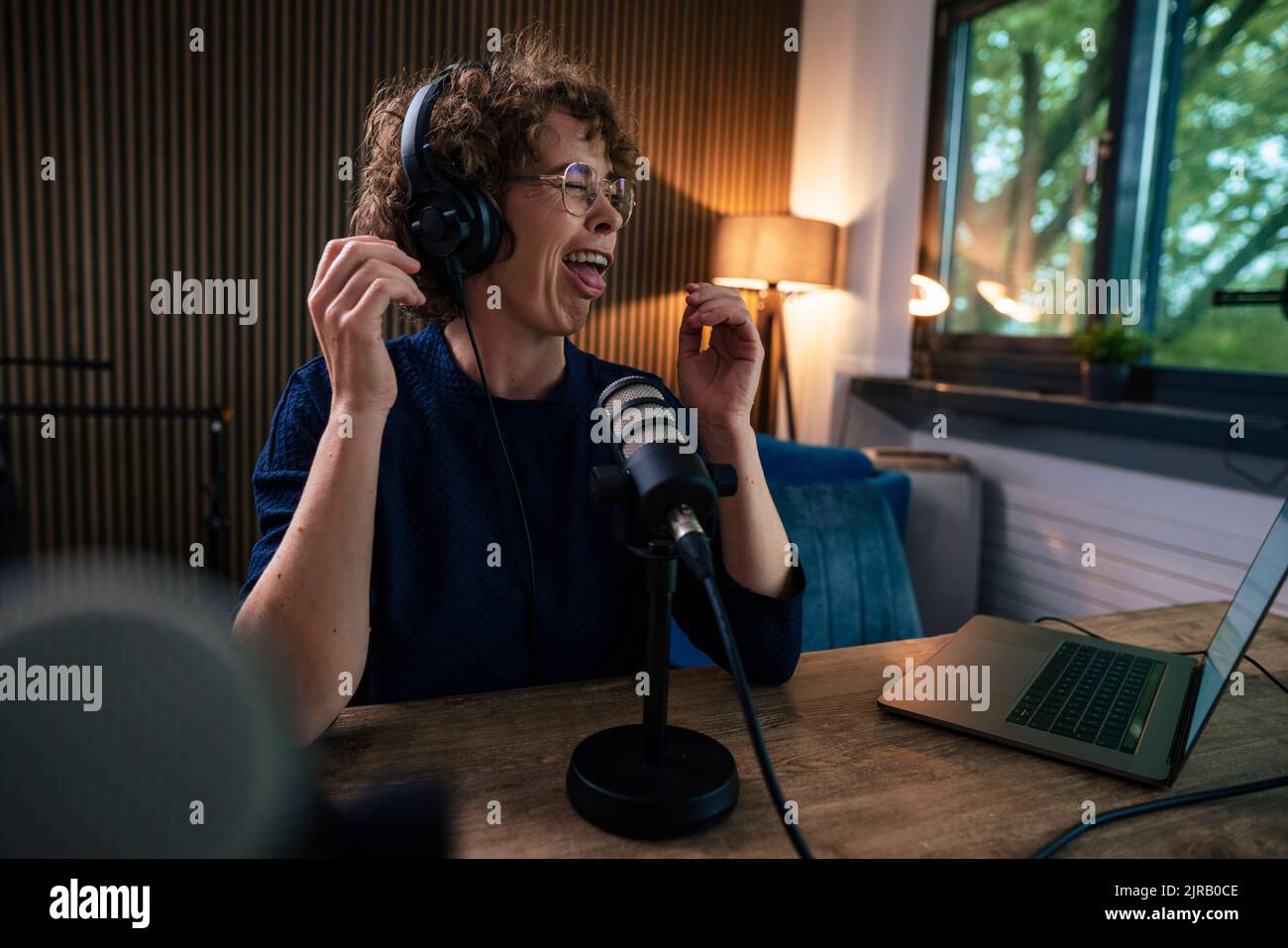 Presenter wearing headset making face sitting with microphone and ...
