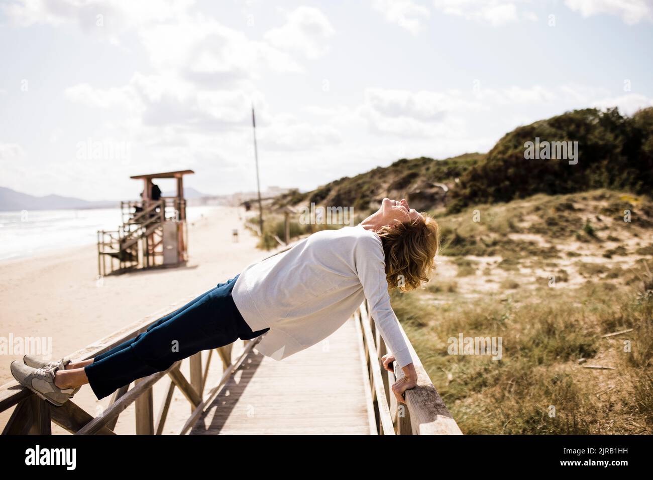 Active mature woman balancing on boardwalk at beach Stock Photo - Alamy
