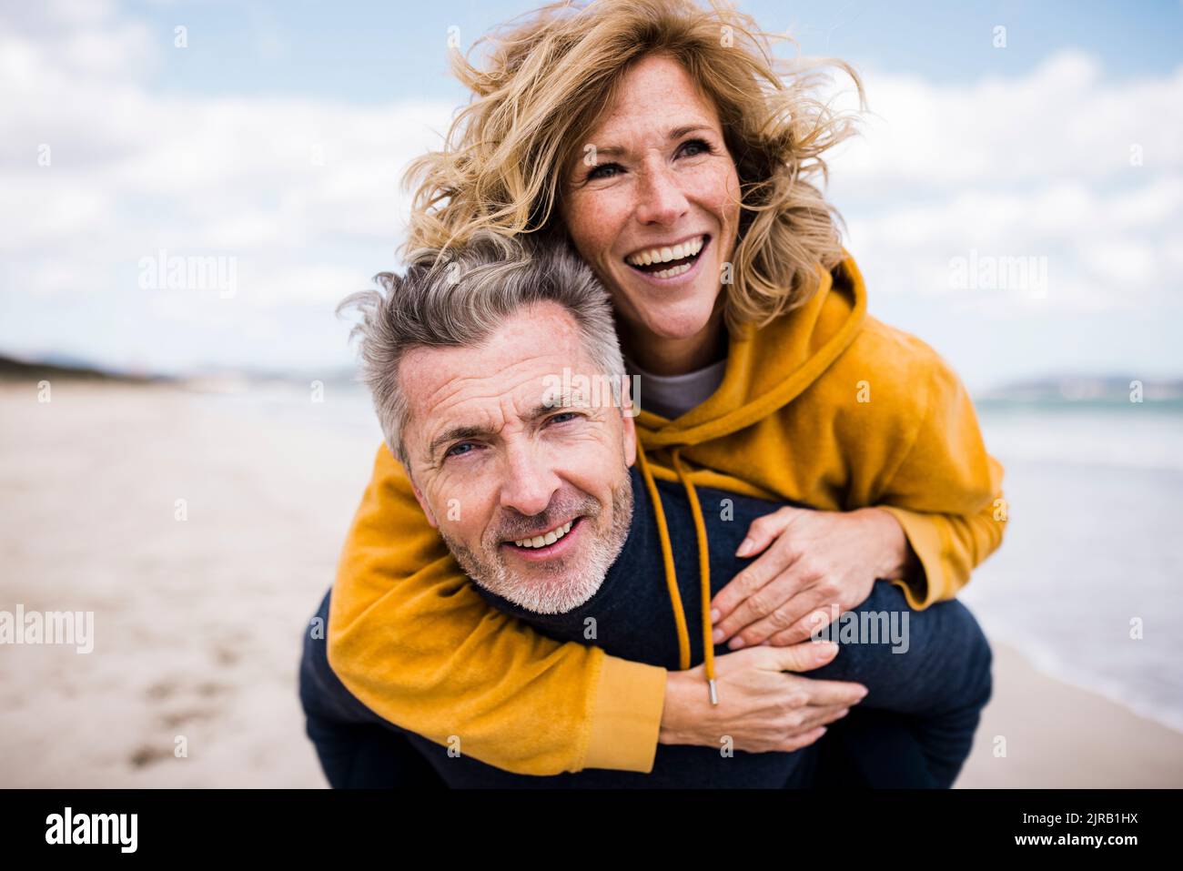 Happy man giving piggyback ride to woman at beach Stock Photo - Alamy