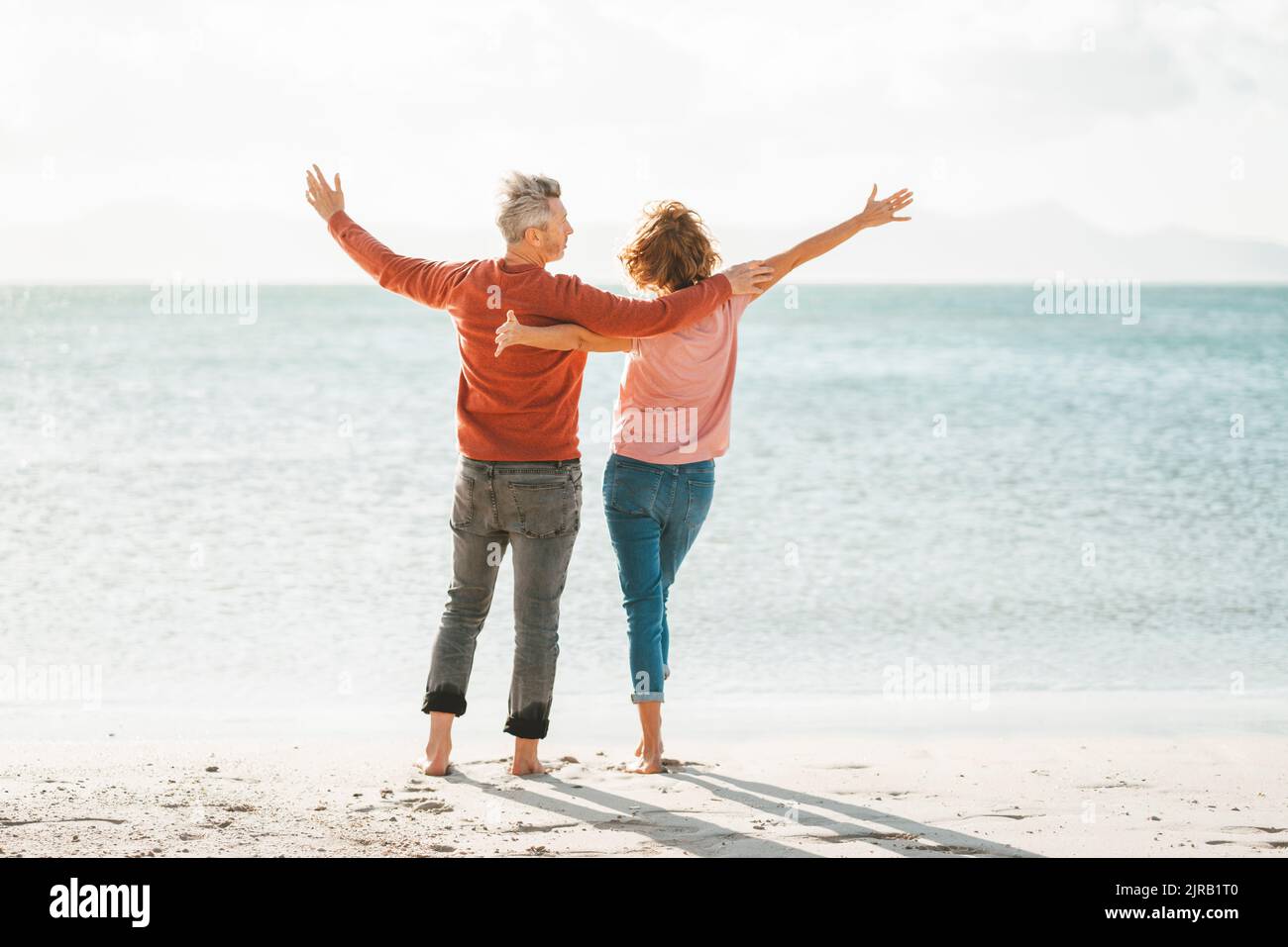 Mature couple with arms outstretched standing on shore at beach Stock ...