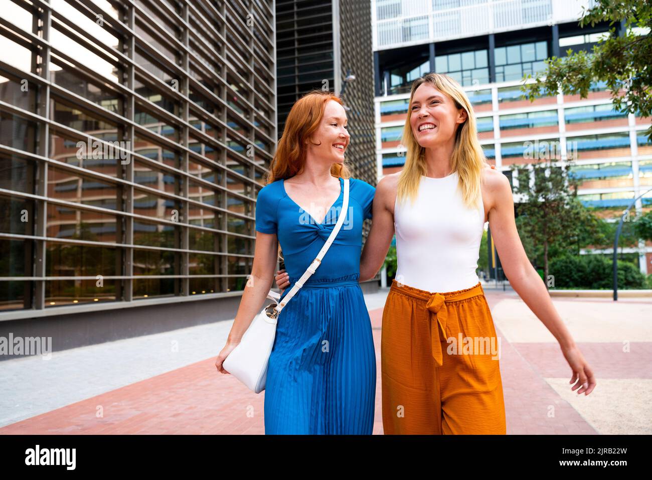 Happy women walking together outside building Stock Photo - Alamy