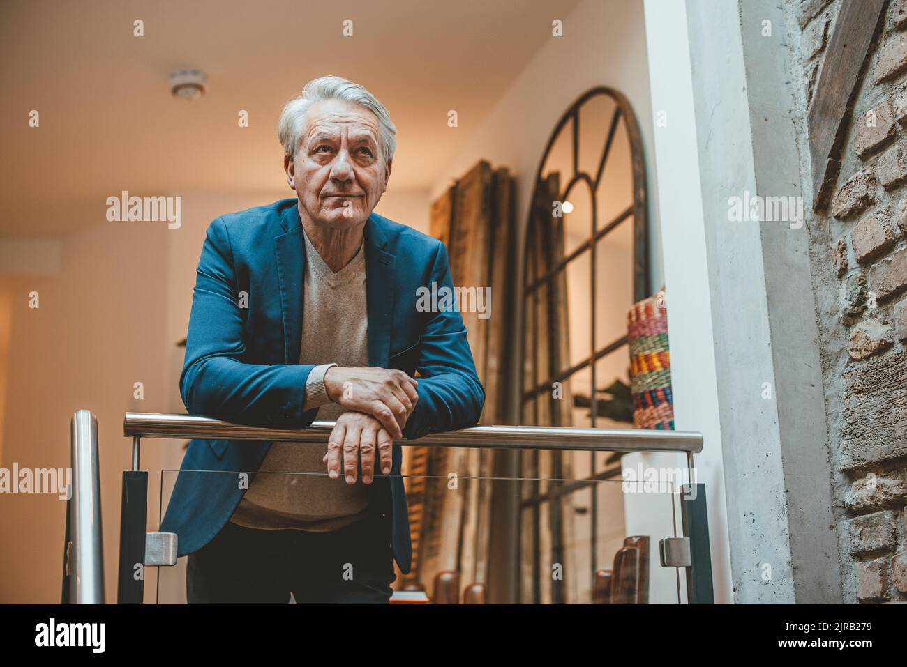 Contemplative businessman leaning on railing Stock Photo - Alamy