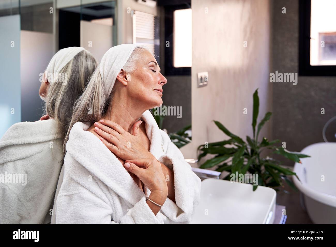 Woman touching neck in bathroom at home Stock Photo - Alamy
