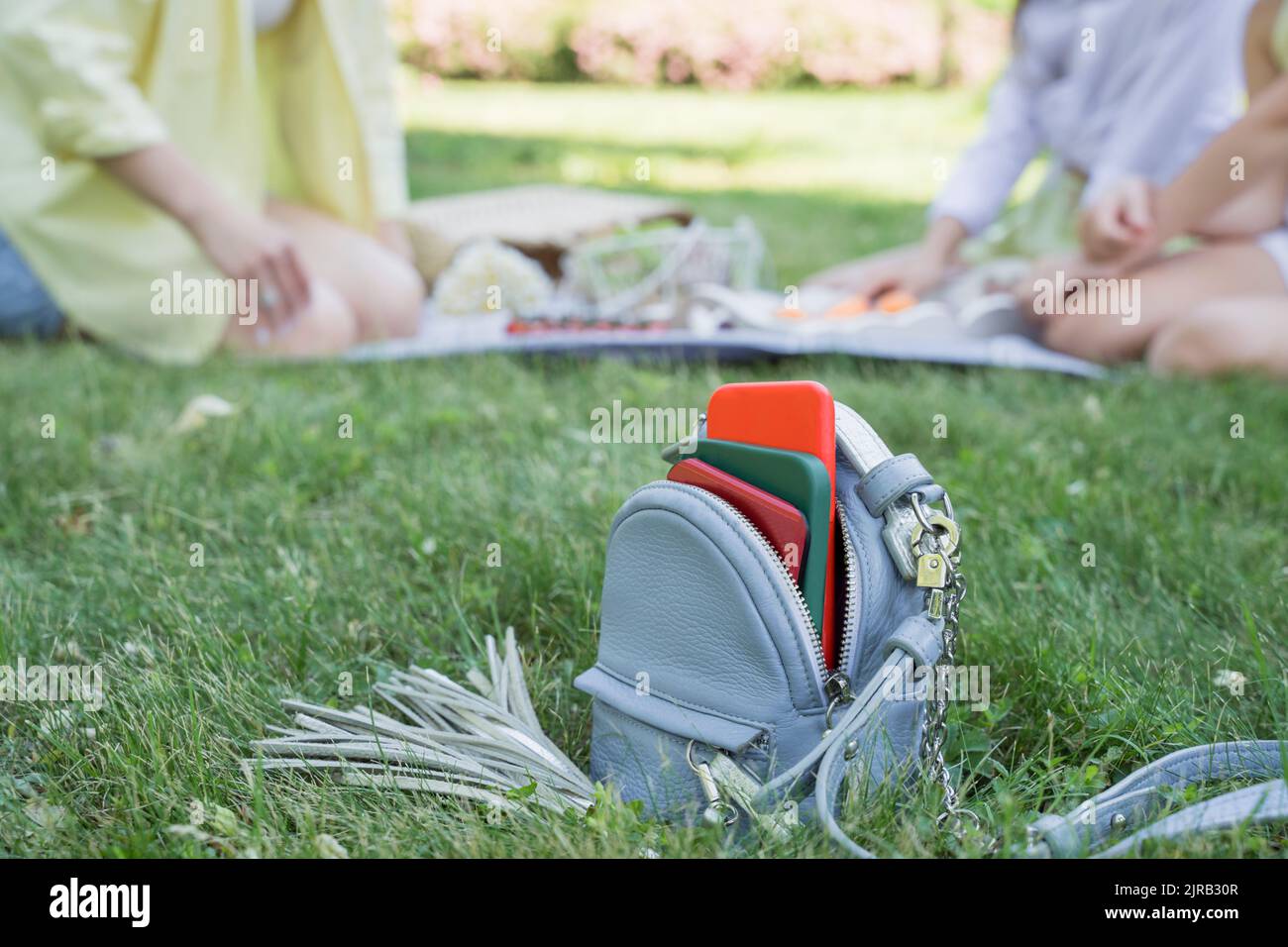 Mobile phones in backpack with family in background at park Stock Photo ...