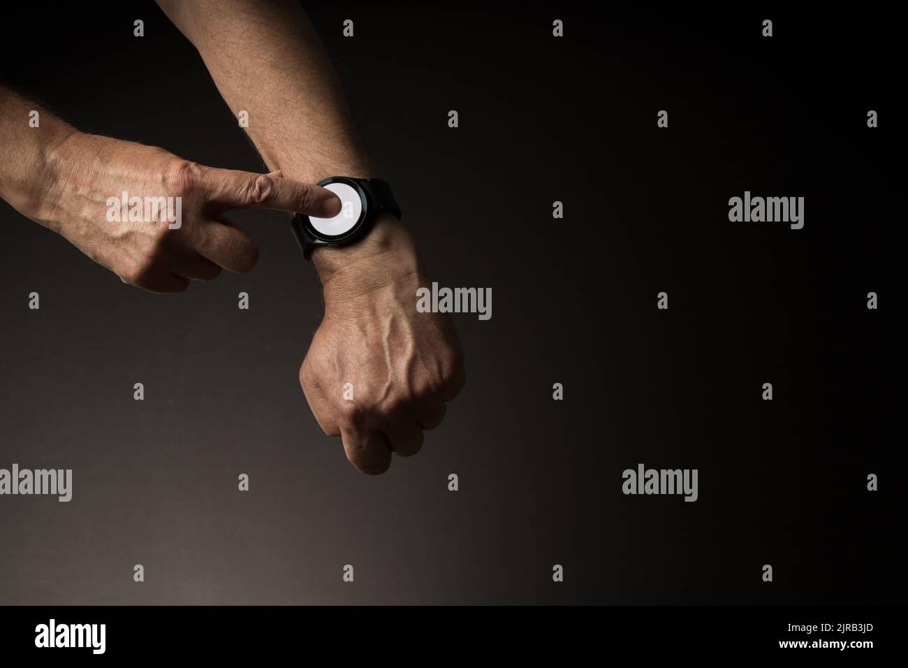 Man's hand with finger pressing smart watch on wrist, displaying blank ...