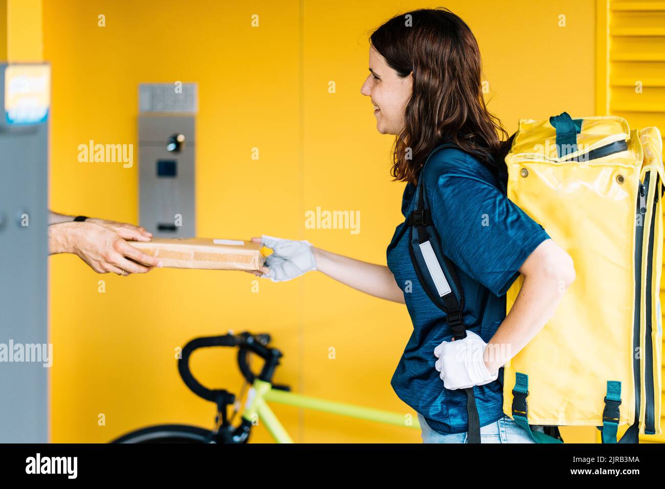 Happy delivery woman giving package to customer Stock Photo - Alamy
