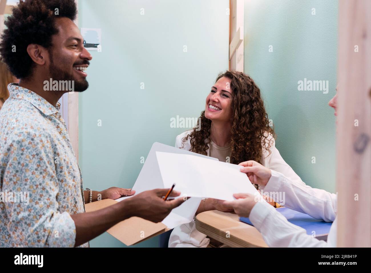 Businessman handing over document to colleague in office Stock Photo ...