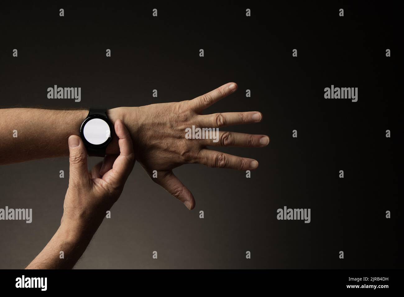 Man's hand with fingers pressing smart watch on wrist, displaying blank ...