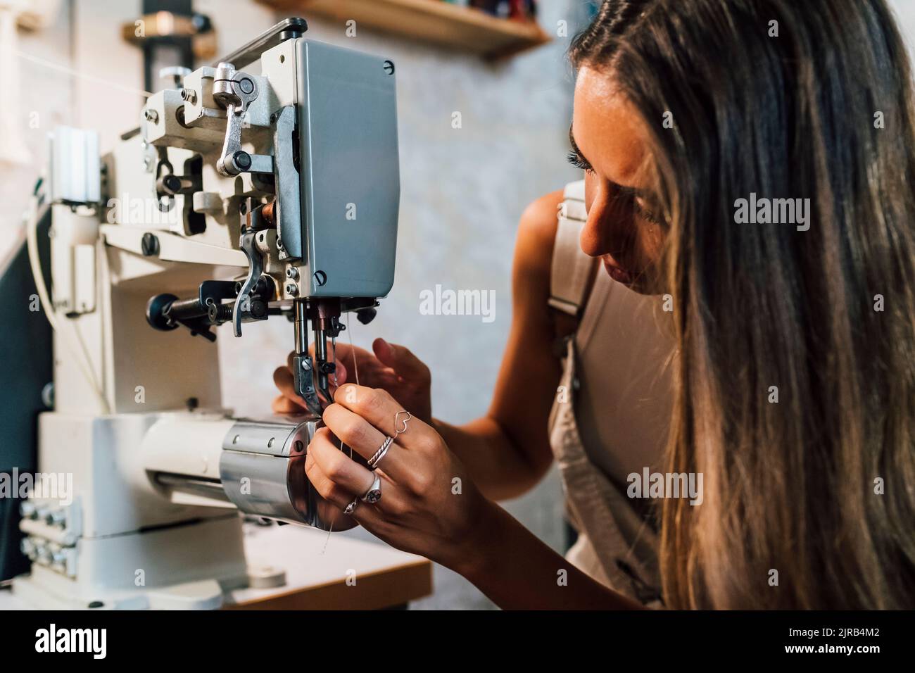 Fashion designer threading needle in sewing machine at workshop Stock ...