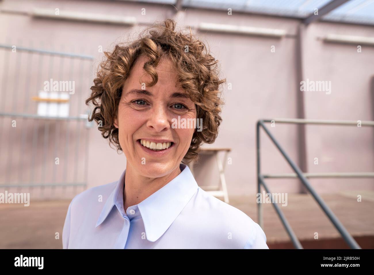 Happy mature real estate agent with brown curly hair Stock Photo - Alamy