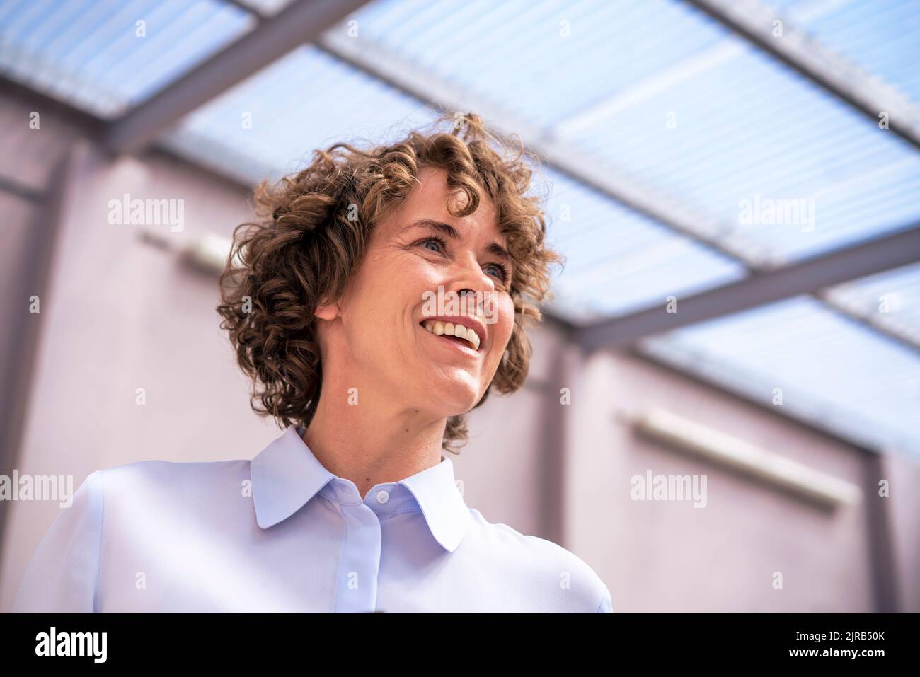 Happy real estate agent with brown curly hair Stock Photo - Alamy