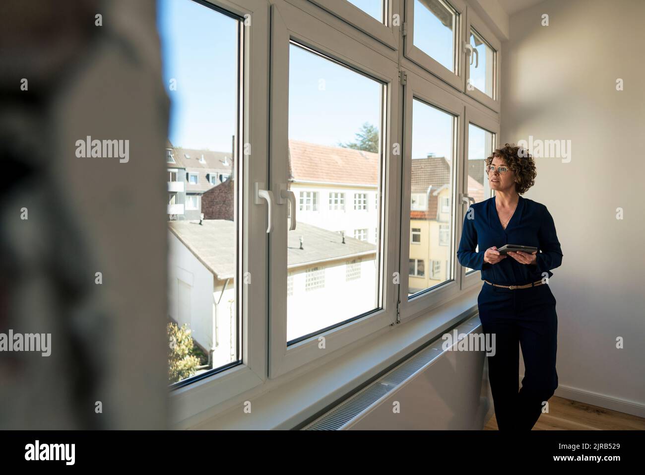 Real estate agent with tablet PC looking through window Stock Photo - Alamy