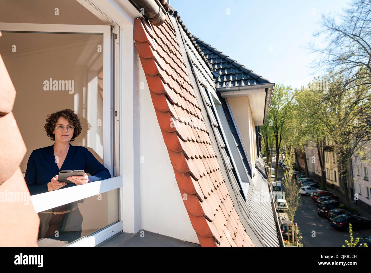 Real estate agent with tablet PC standing at window Stock Photo - Alamy