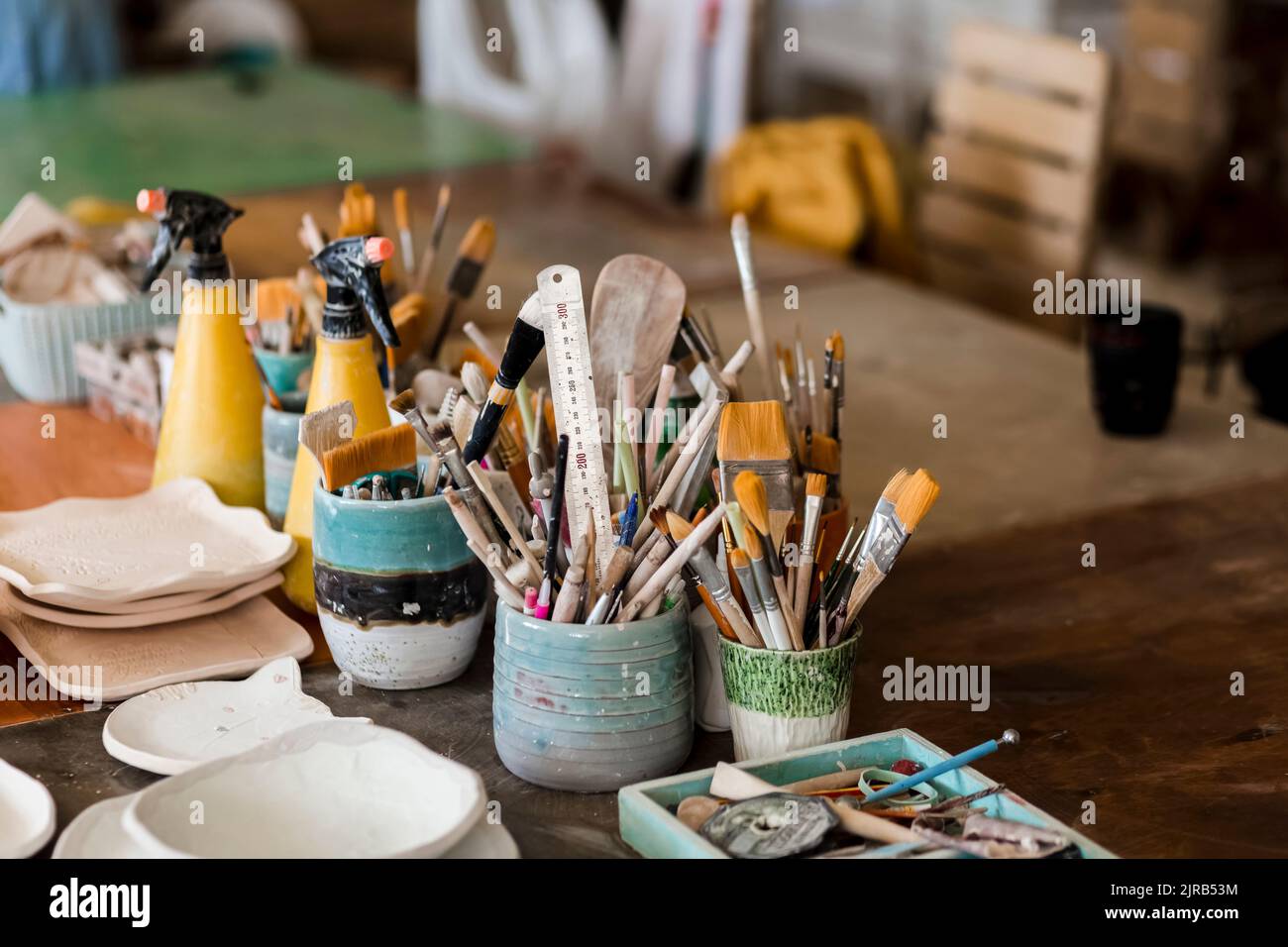 Brushes and ceramic plates on workbench at art studio Stock Photo - Alamy