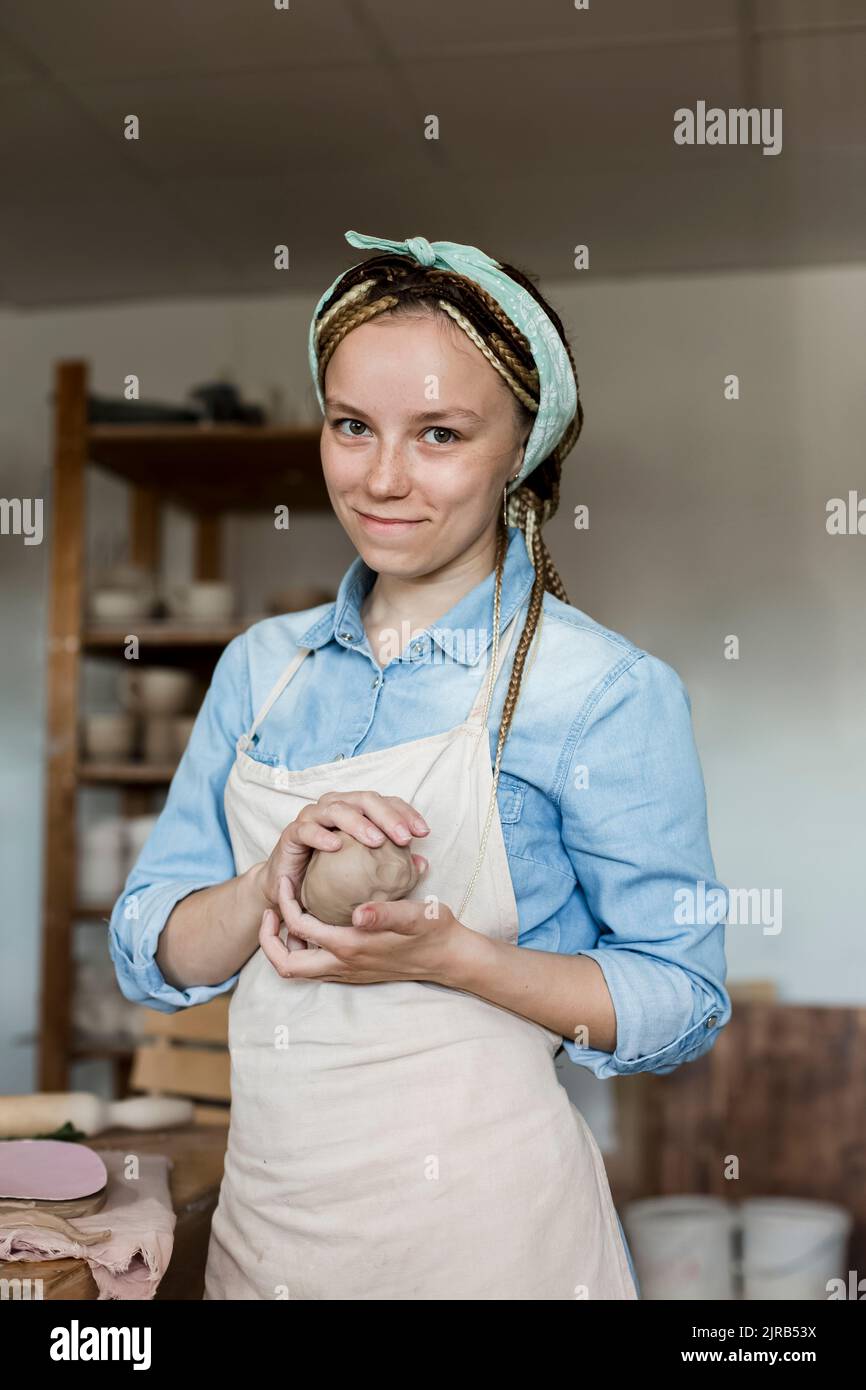 Smiling craftsperson holding clay at art studio Stock Photo - Alamy