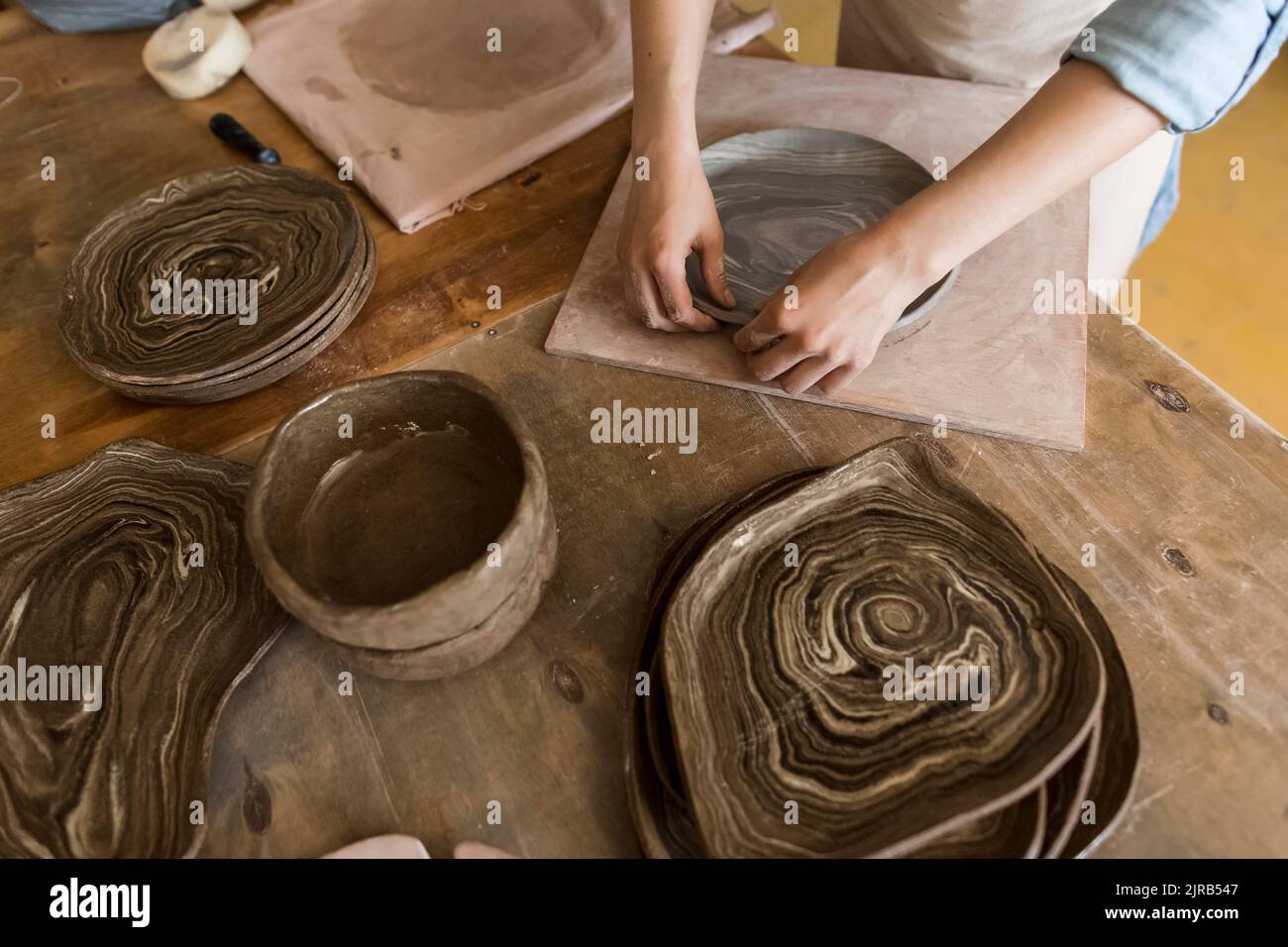 Hands of potter making plate with clay on workbench Stock Photo - Alamy