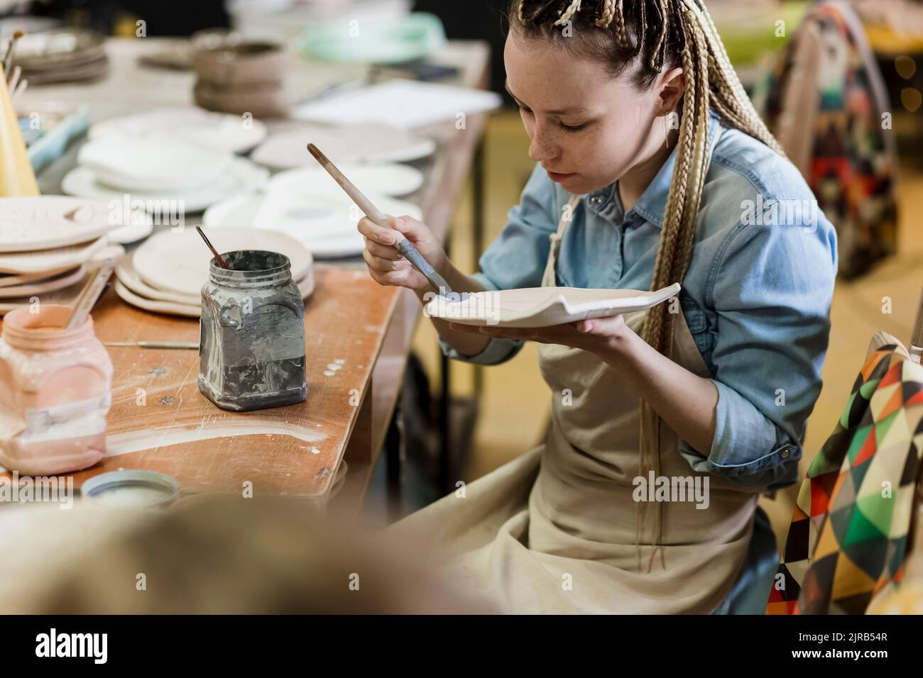 Craftsperson painting earthen plate at workshop Stock Photo - Alamy