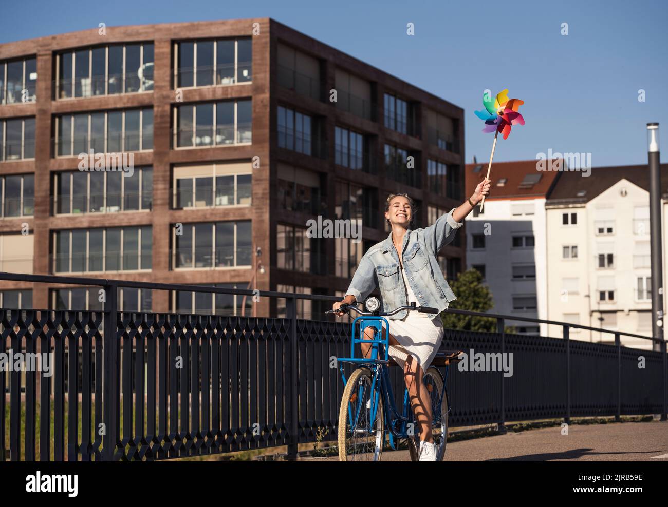 Happy woman with pinwheel toy riding bicycle by railing Stock Photo - Alamy
