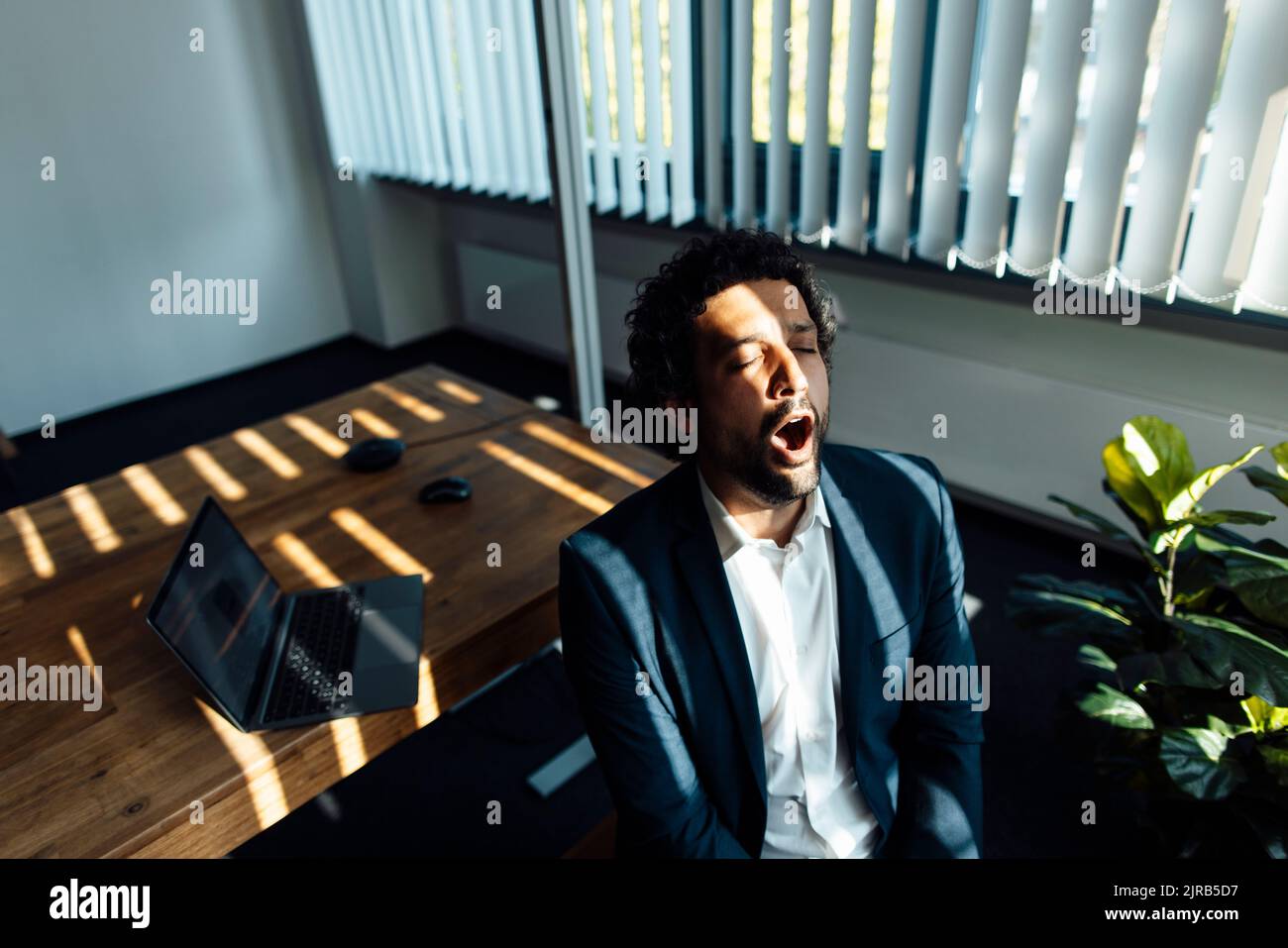 Tired businessman yawning at workplace Stock Photo - Alamy
